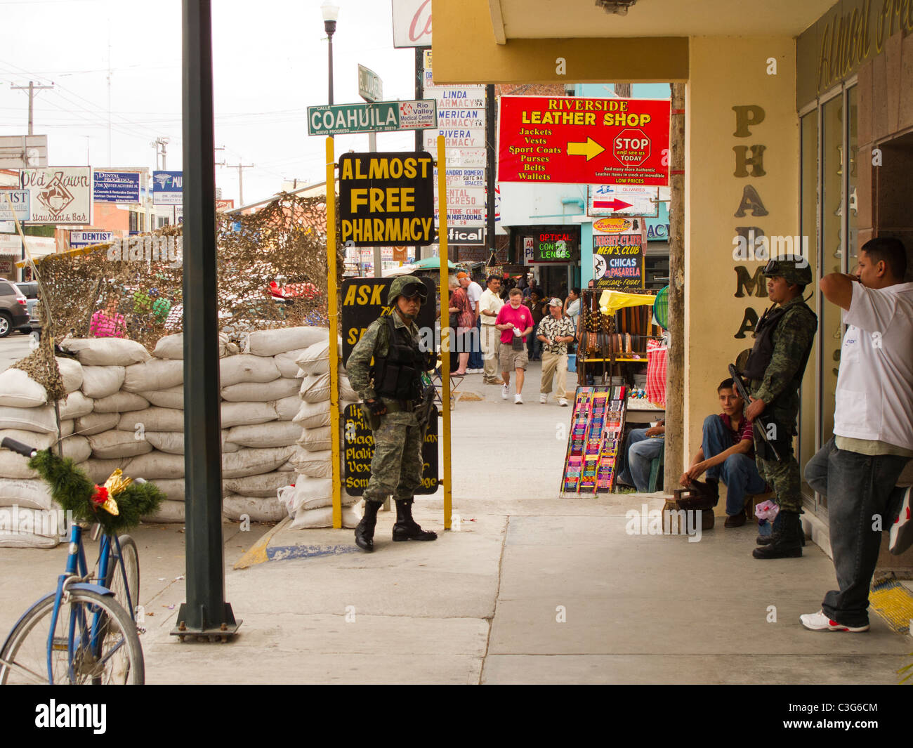 Armed Mexican soldiers stand near their fortified post while tourists ...