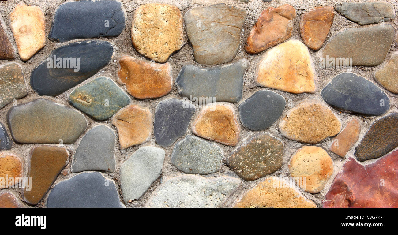 Stone wall of the house from different color of stones in a laying ...