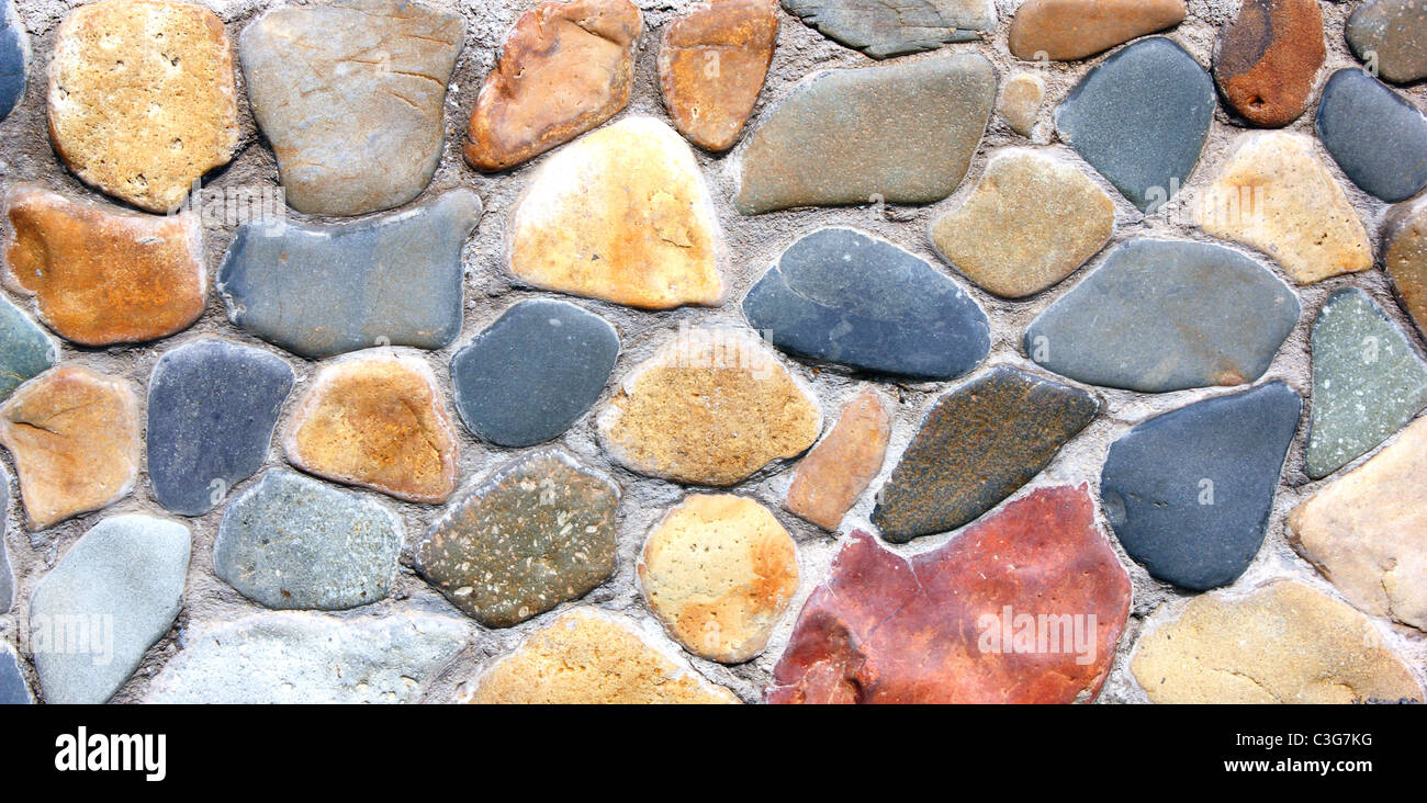 Stone wall of the house from different color of stones in a laying ...