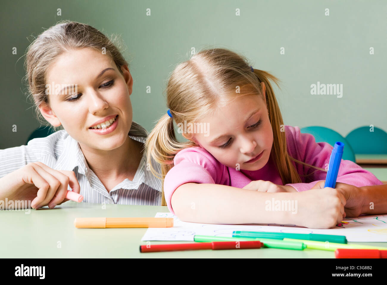Portrait of diligent girl drawing something under tending of her ...