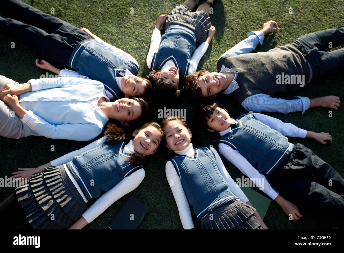 Teacher and students lying in a circle on grass Stock Photo - Alamy