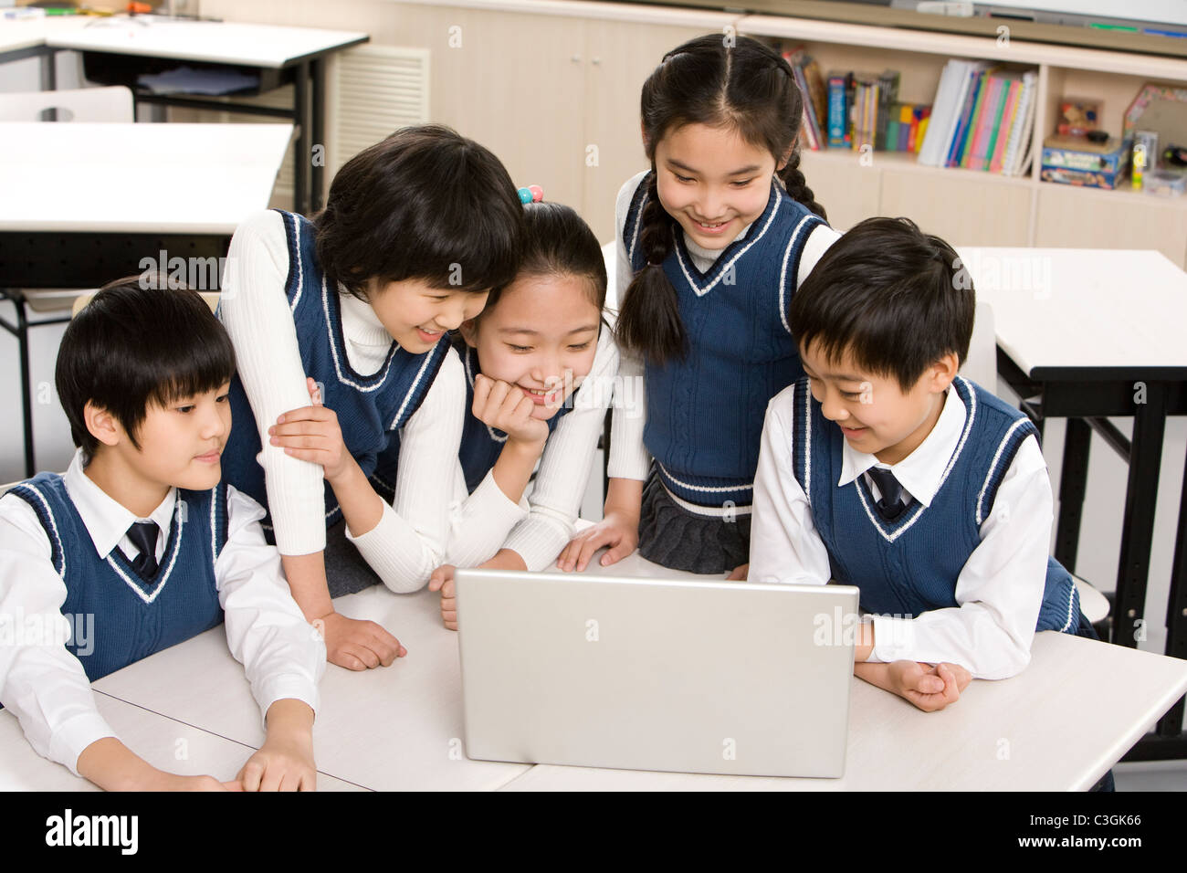 Students gathered around a computer in the classroom Stock Photo - Alamy