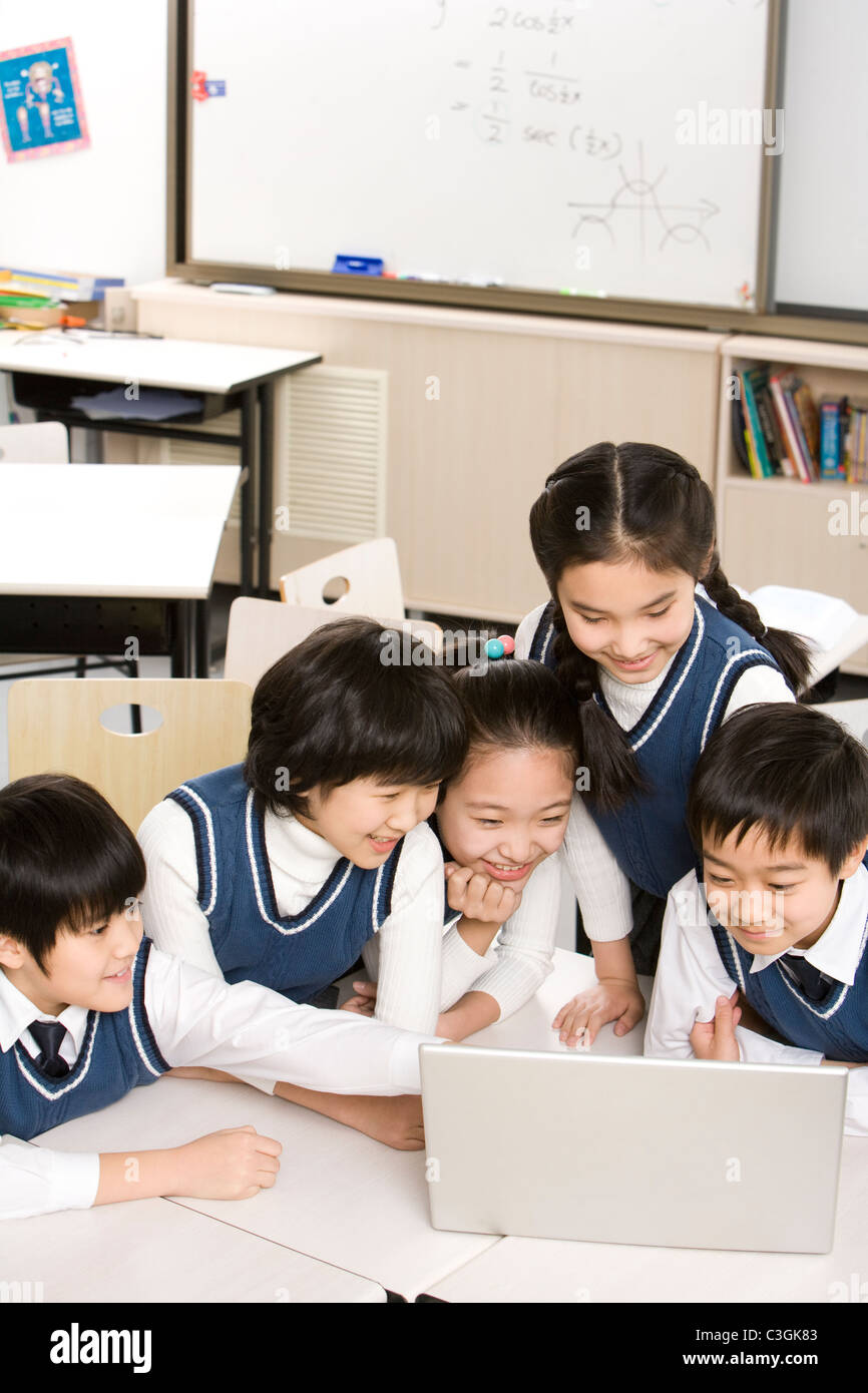 Students gathered around a computer in the classroom Stock Photo - Alamy