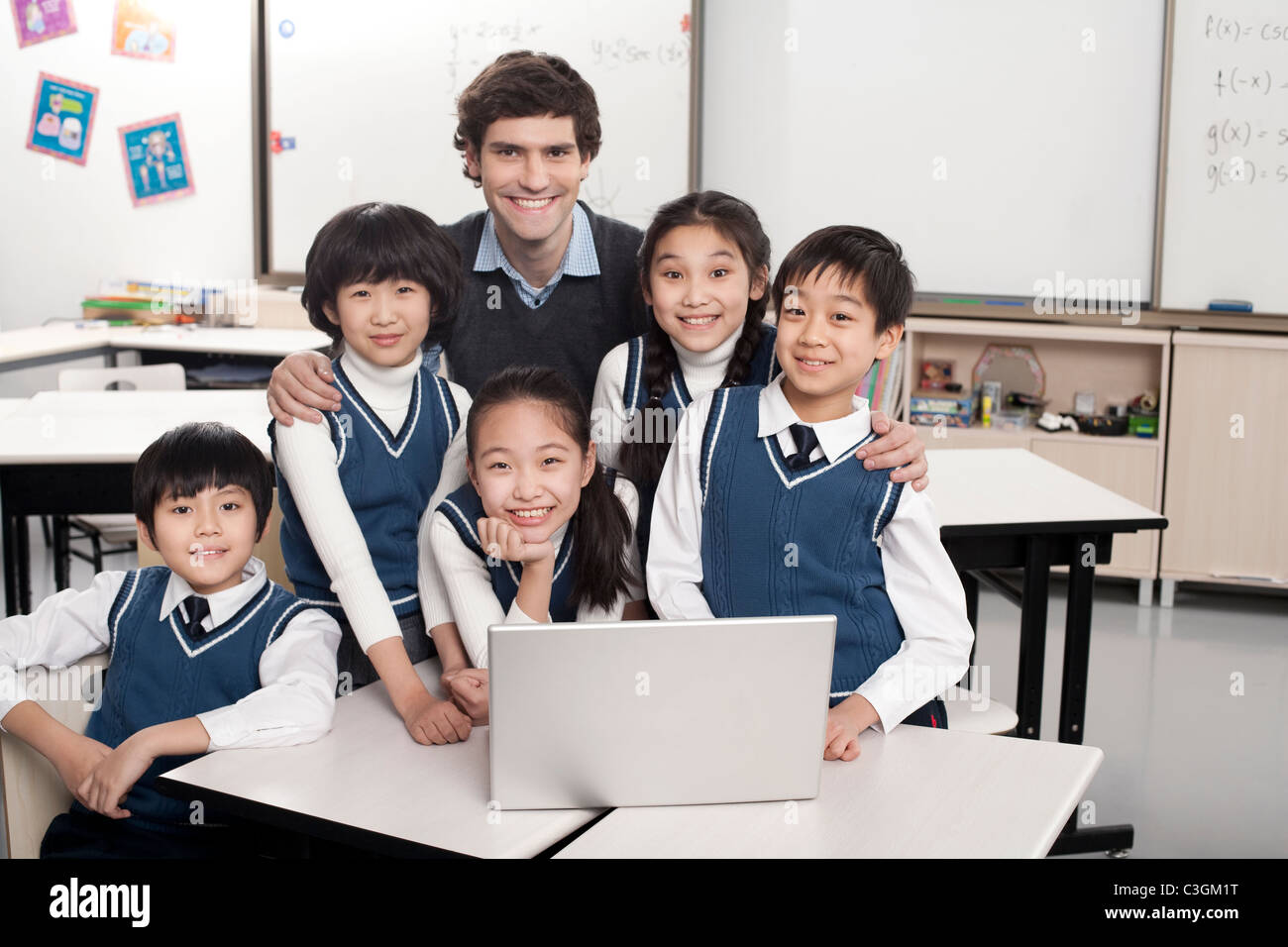 Students and teacher gathered around a computer in the classroom Stock ...