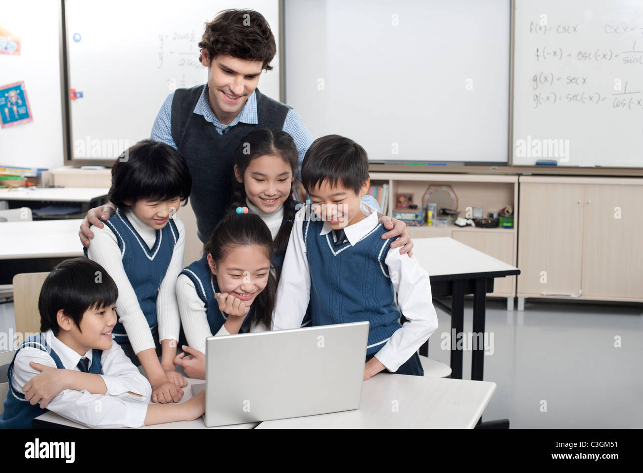 Students and teacher gathered around a computer in the classroom Stock ...