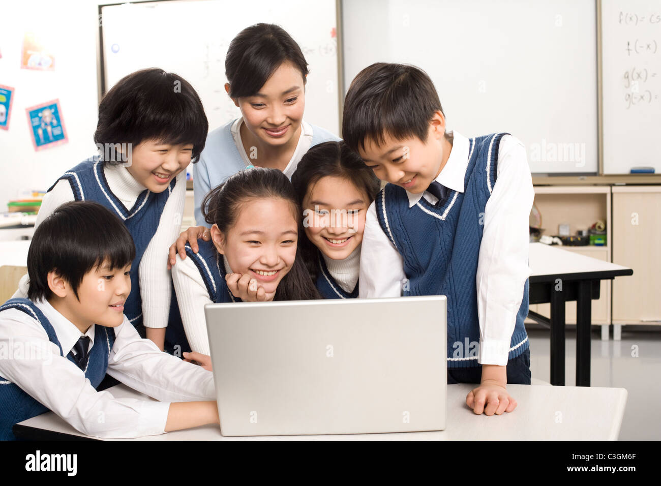 Students and teacher gathered around a computer in the classroom Stock ...