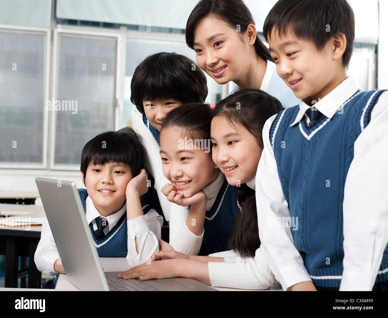 Students and teacher gathered around a computer in the classroom Stock ...