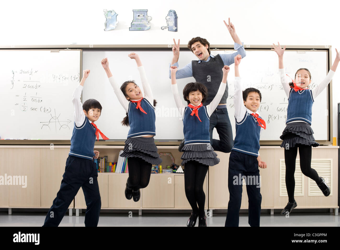 Teacher and students jumping in front of whiteboard Stock Photo - Alamy