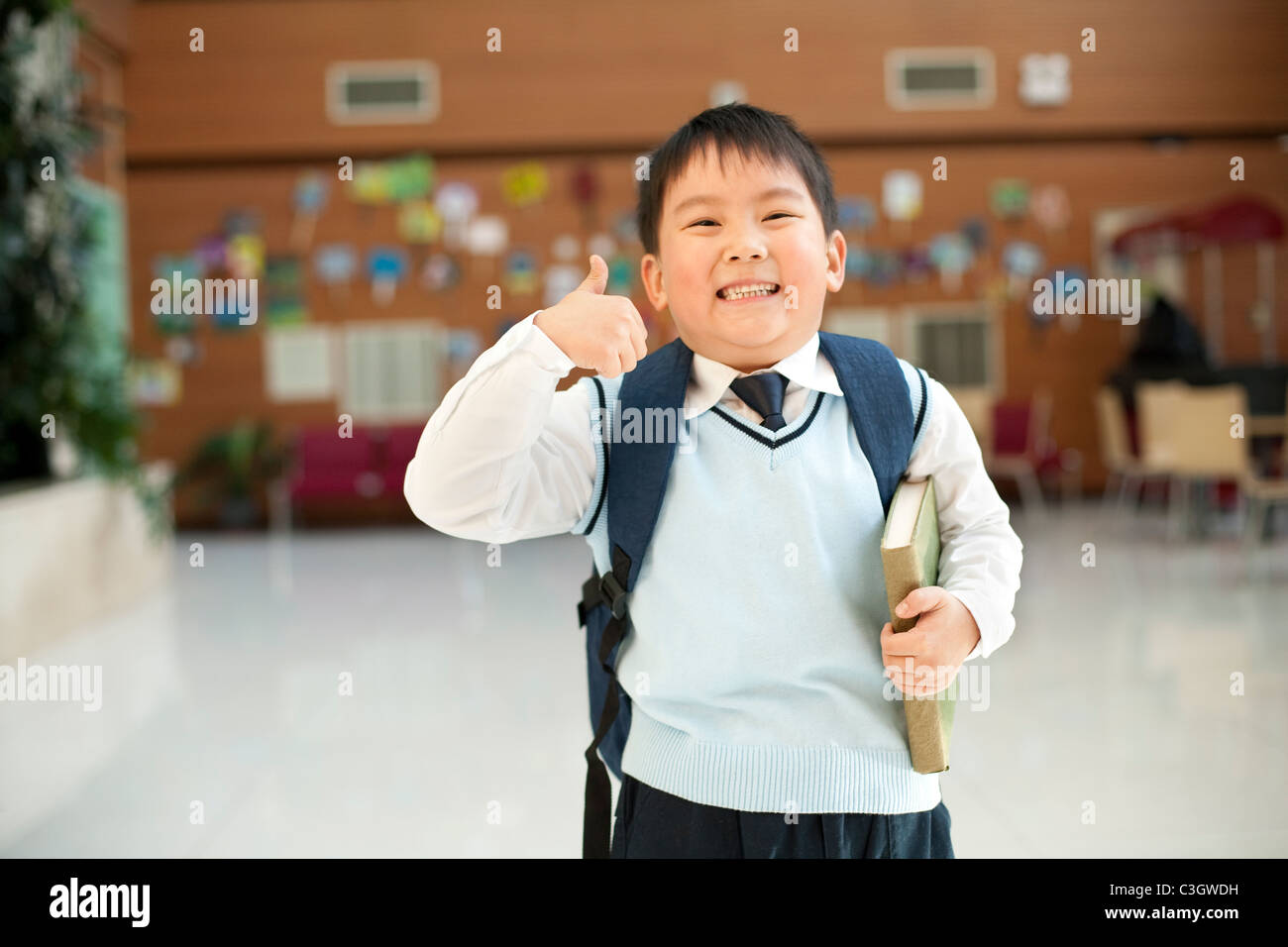 Young student giving a thumbs up while holding a book Stock Photo - Alamy