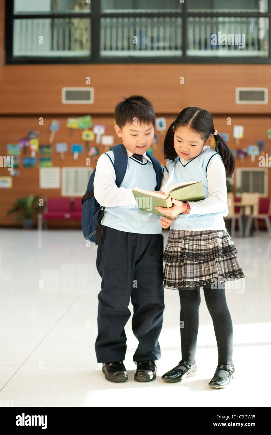 Young students huddle together reading a book Stock Photo - Alamy