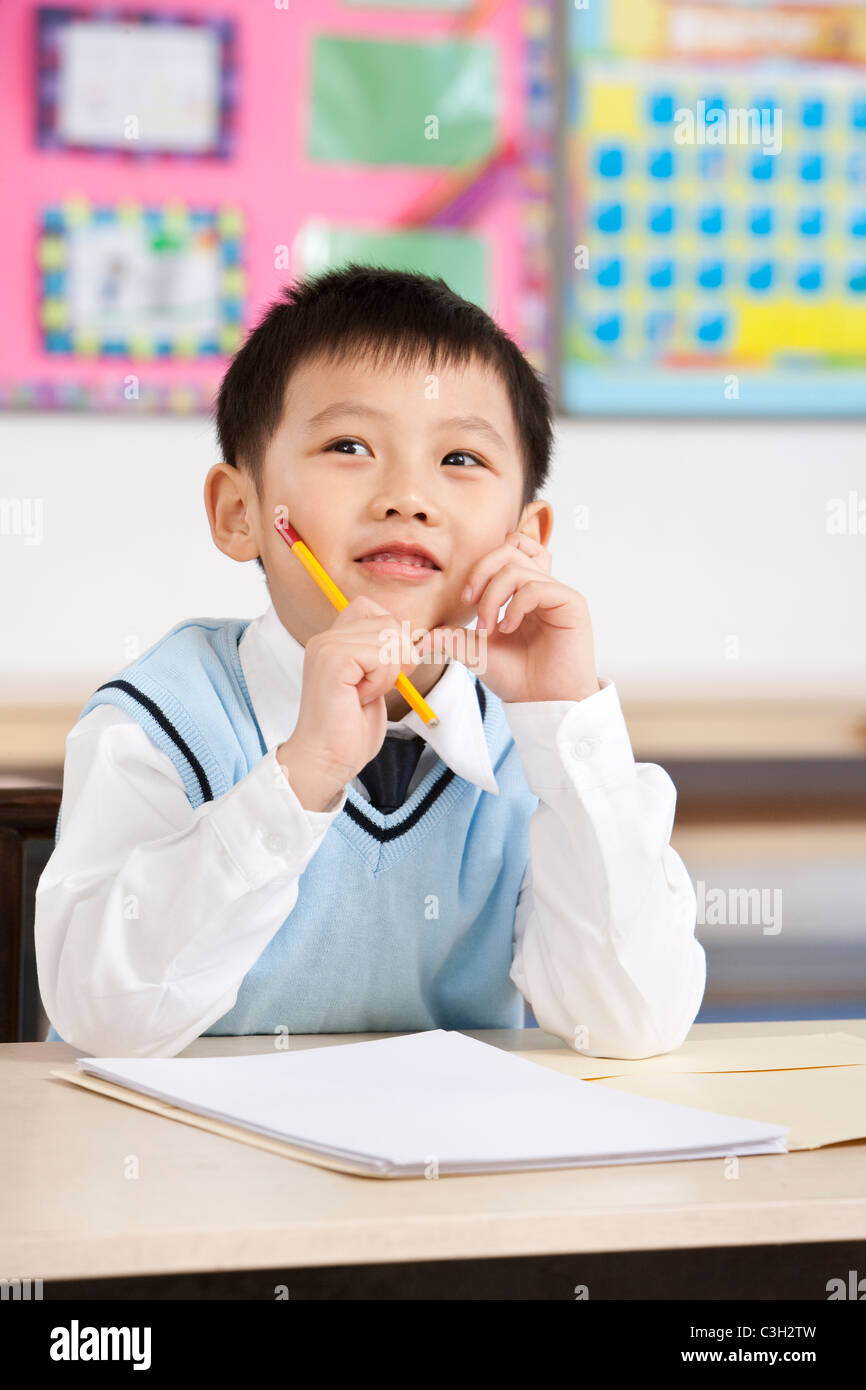 Young boy thinking about his work in class Stock Photo - Alamy