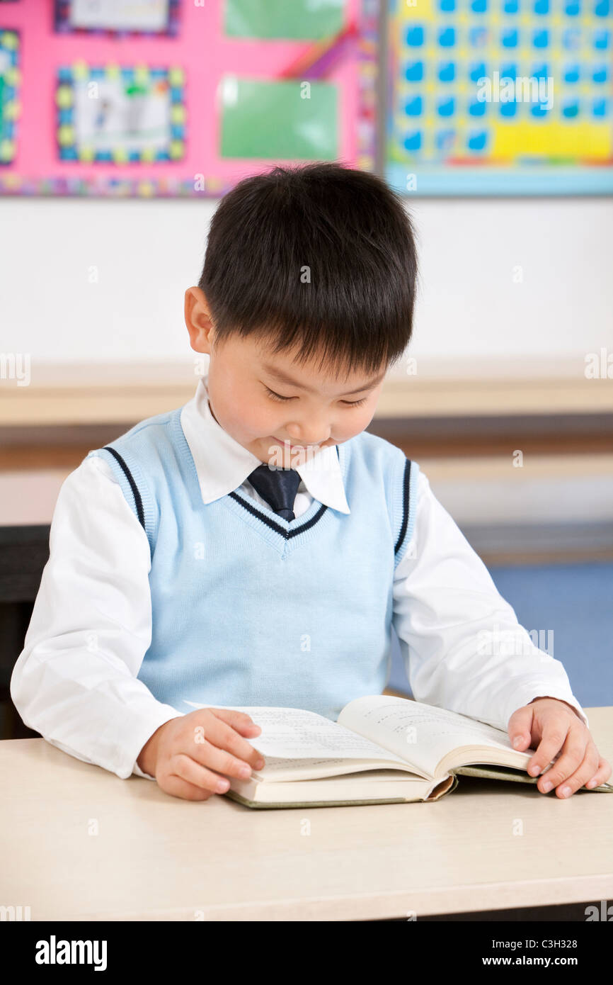 Young boy reading at his desk in a classroom Stock Photo - Alamy