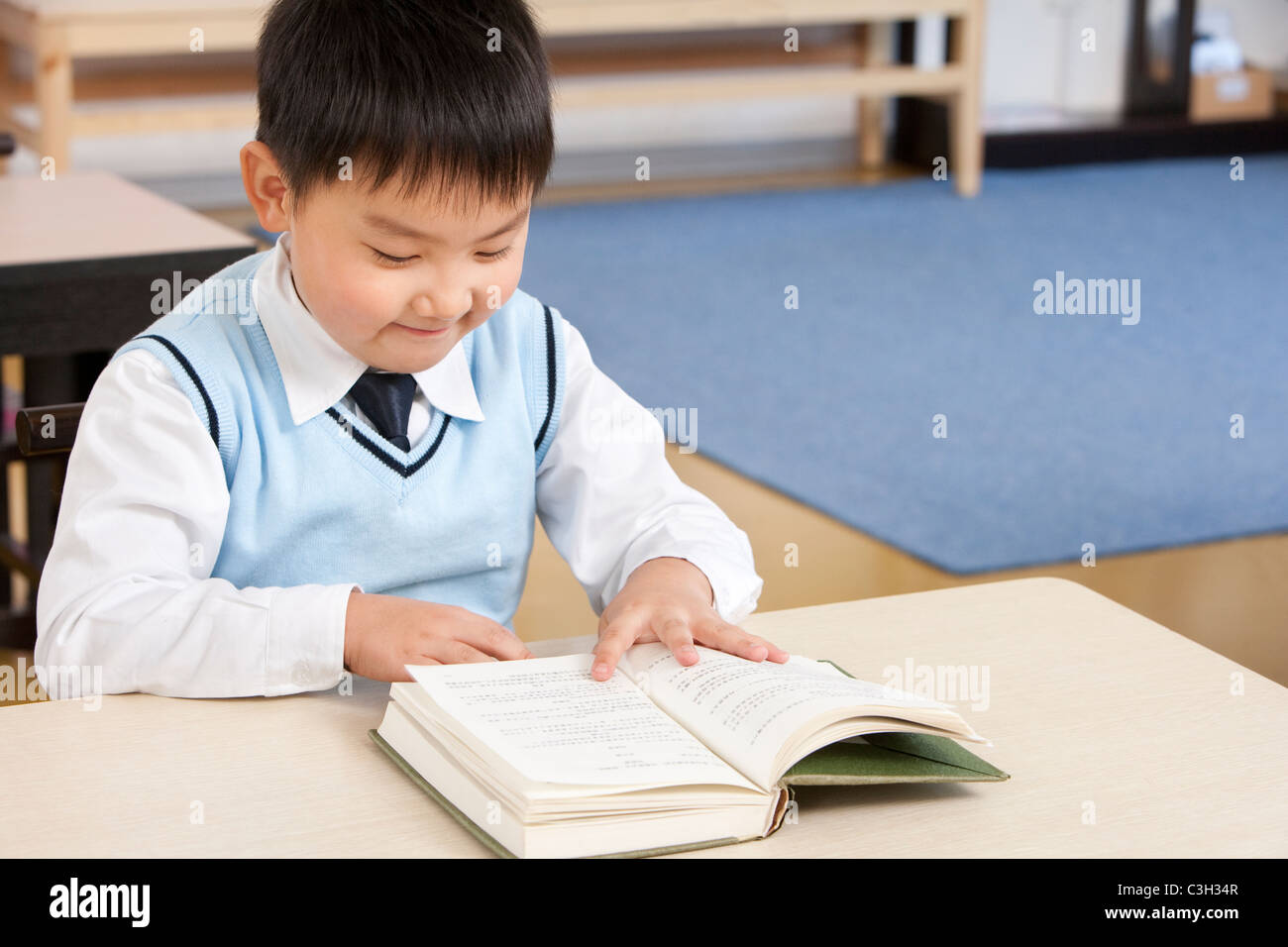Young boy reading at his desk in a classroom Stock Photo - Alamy