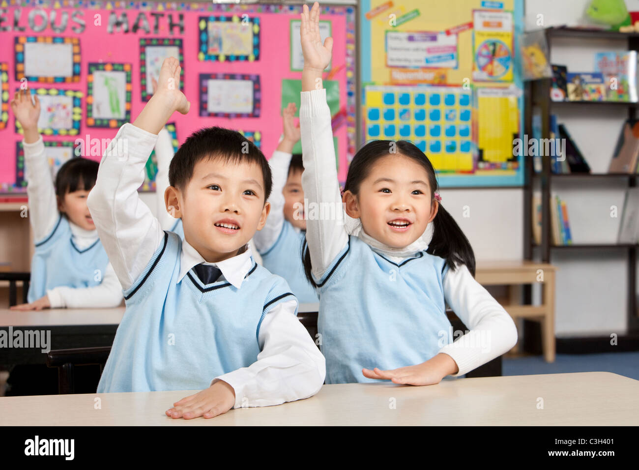 Students raising hands in the classroom Stock Photo - Alamy