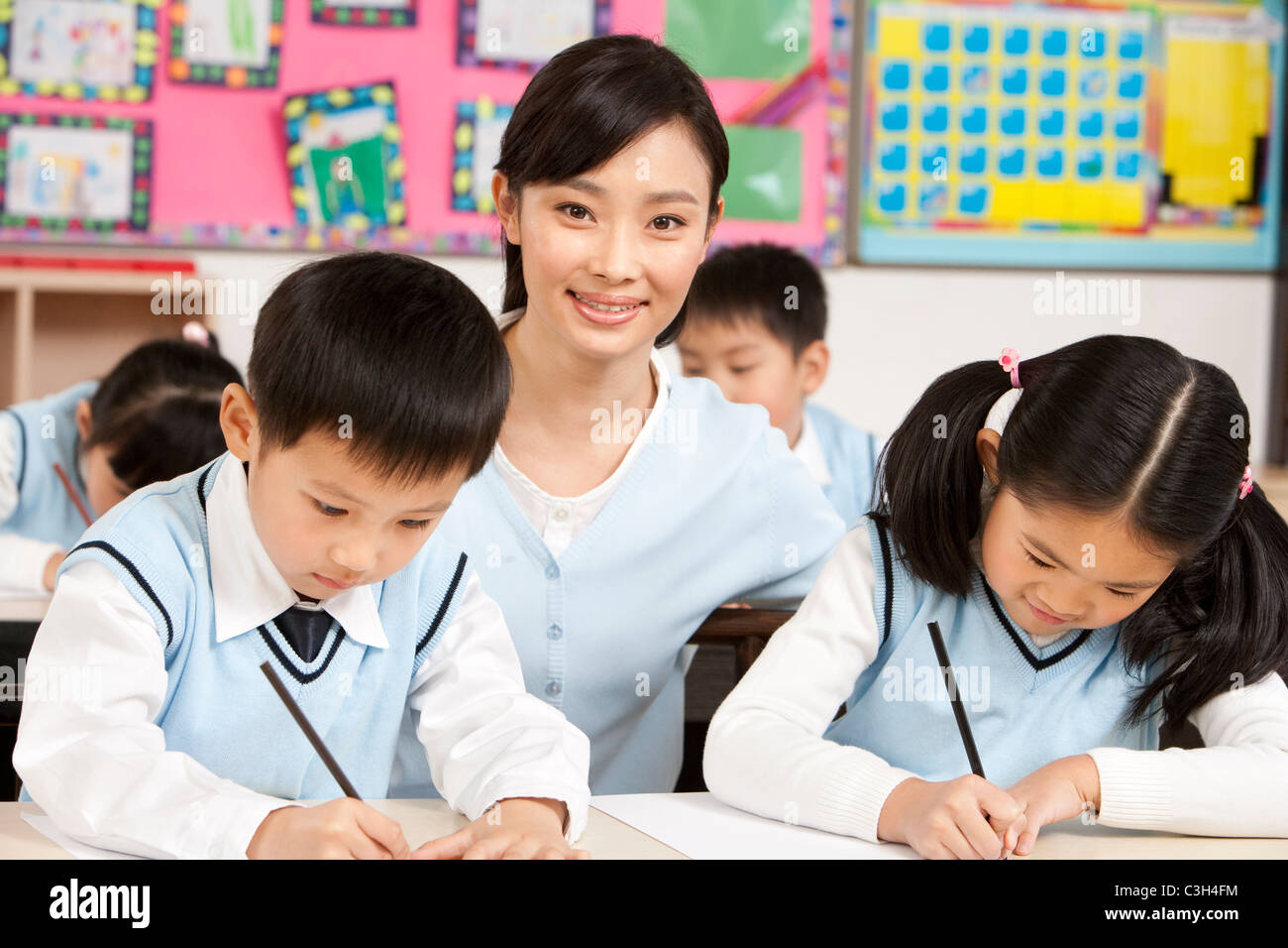 Teacher assisting students in class Stock Photo - Alamy