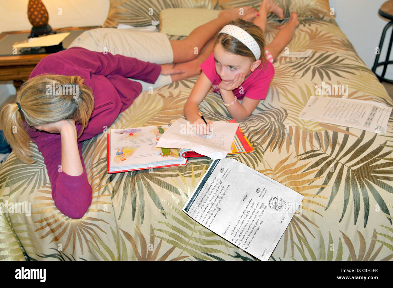 Mother helping her 2nd grade daughter do homework on the bed Stock ...