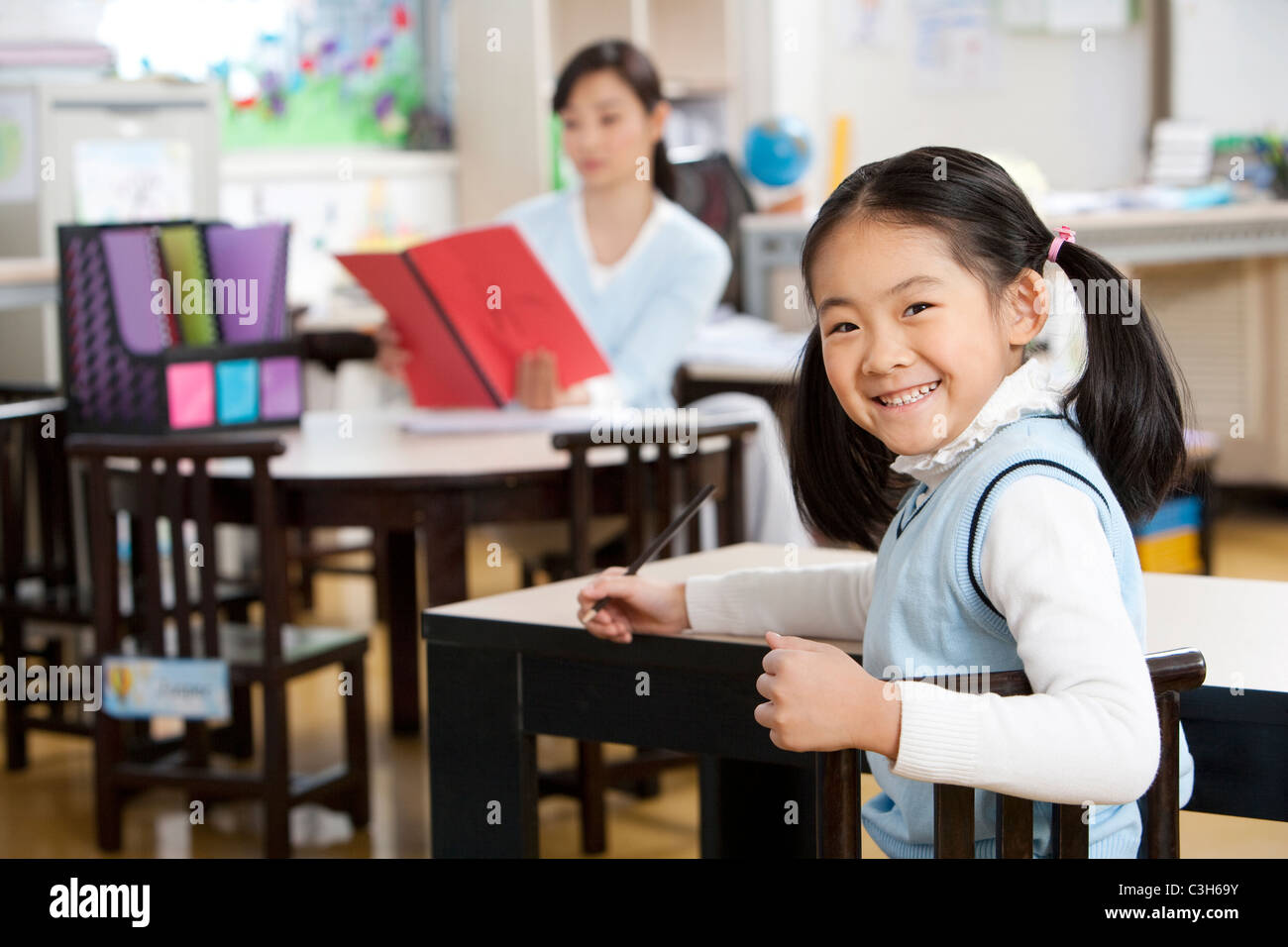 Young student looking over her shoulder smiling in class Stock Photo ...