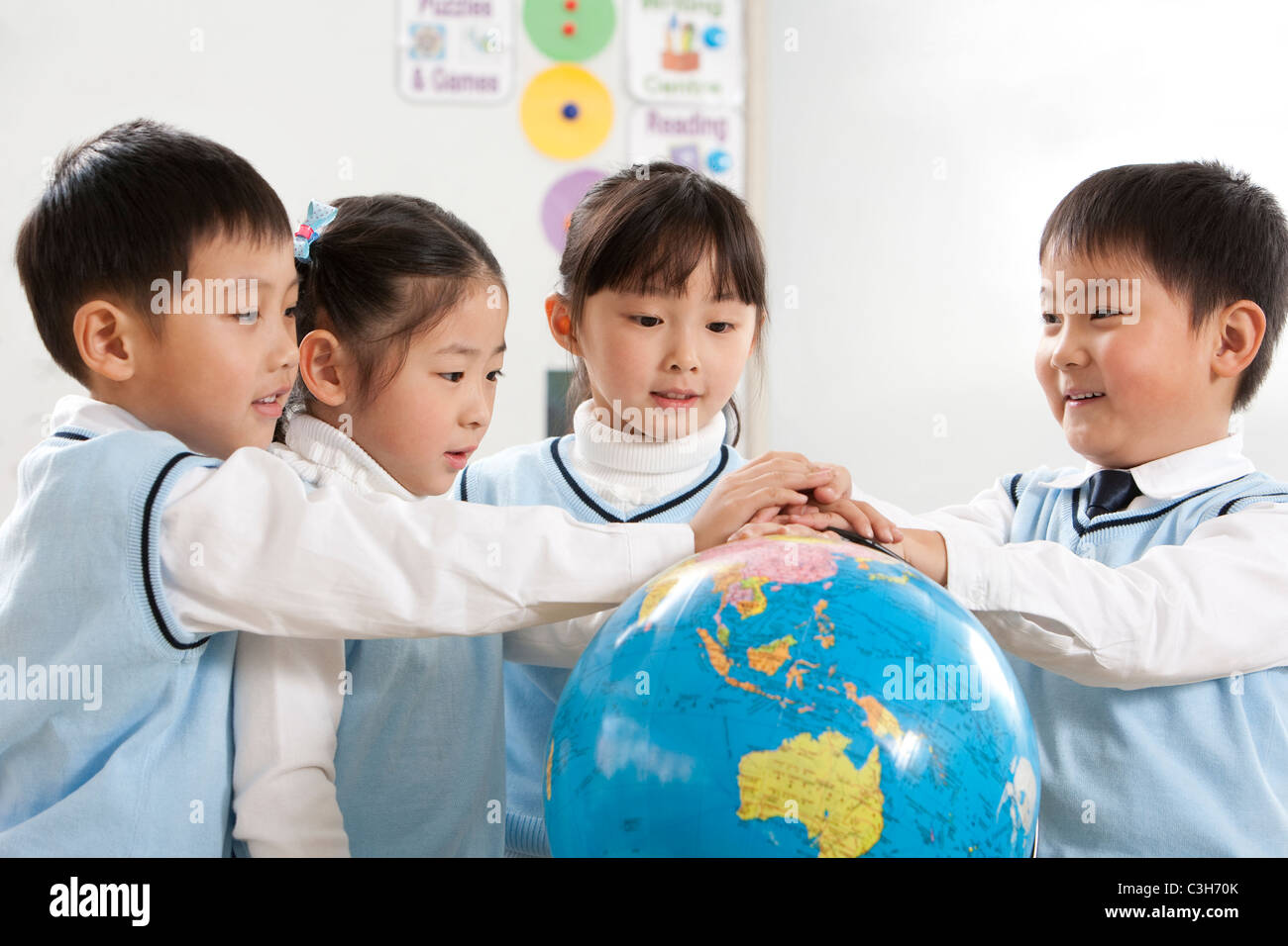 Four curious young students gathered around a globe Stock Photo - Alamy
