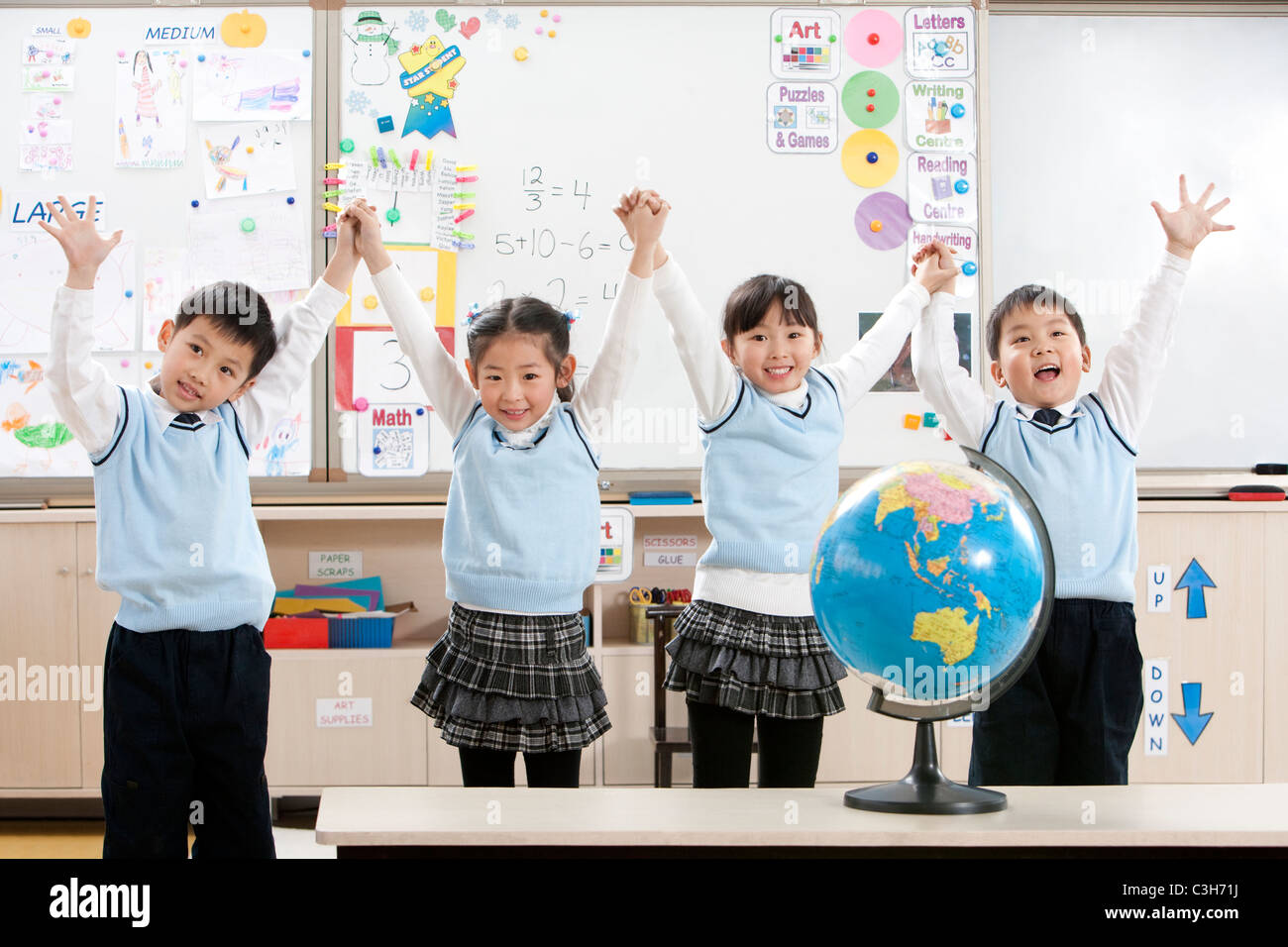 Four young students holding hands up high Stock Photo - Alamy
