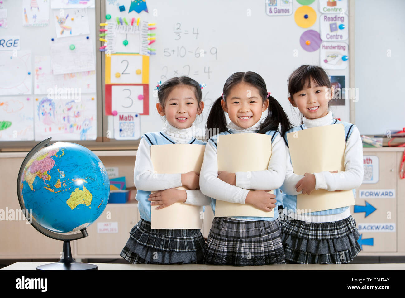 Three young students holding folders and smiling Stock Photo - Alamy