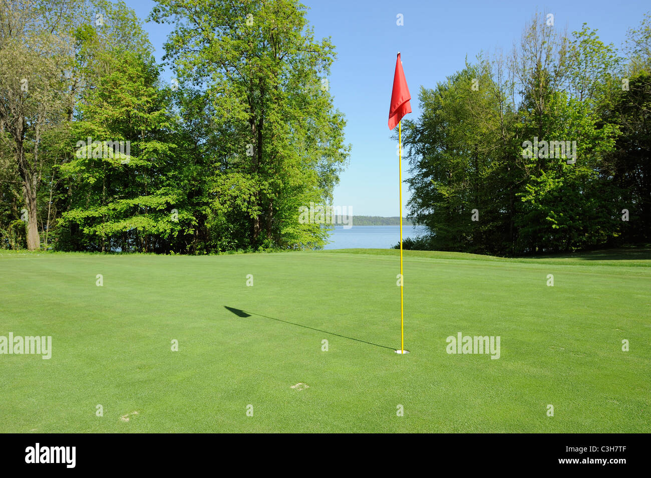 Golf course with flag at a lake Stock Photo - Alamy