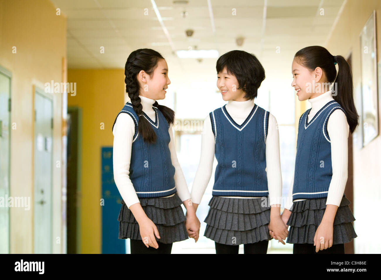 Three female students talking in the school hallway Stock Photo - Alamy