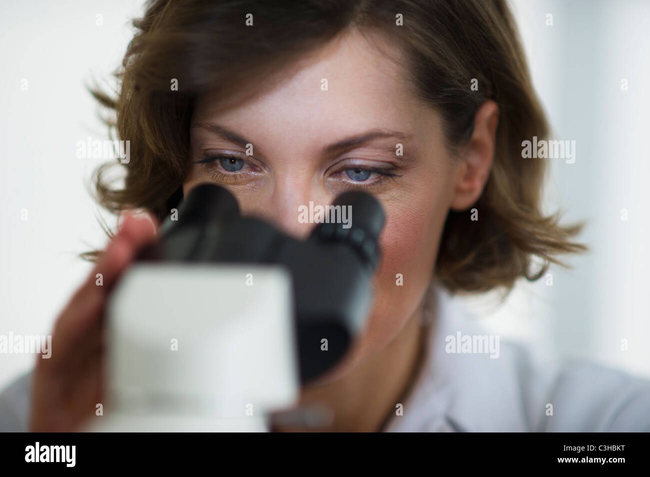 Woman in laboratory looking through microscope Stock Photo - Alamy