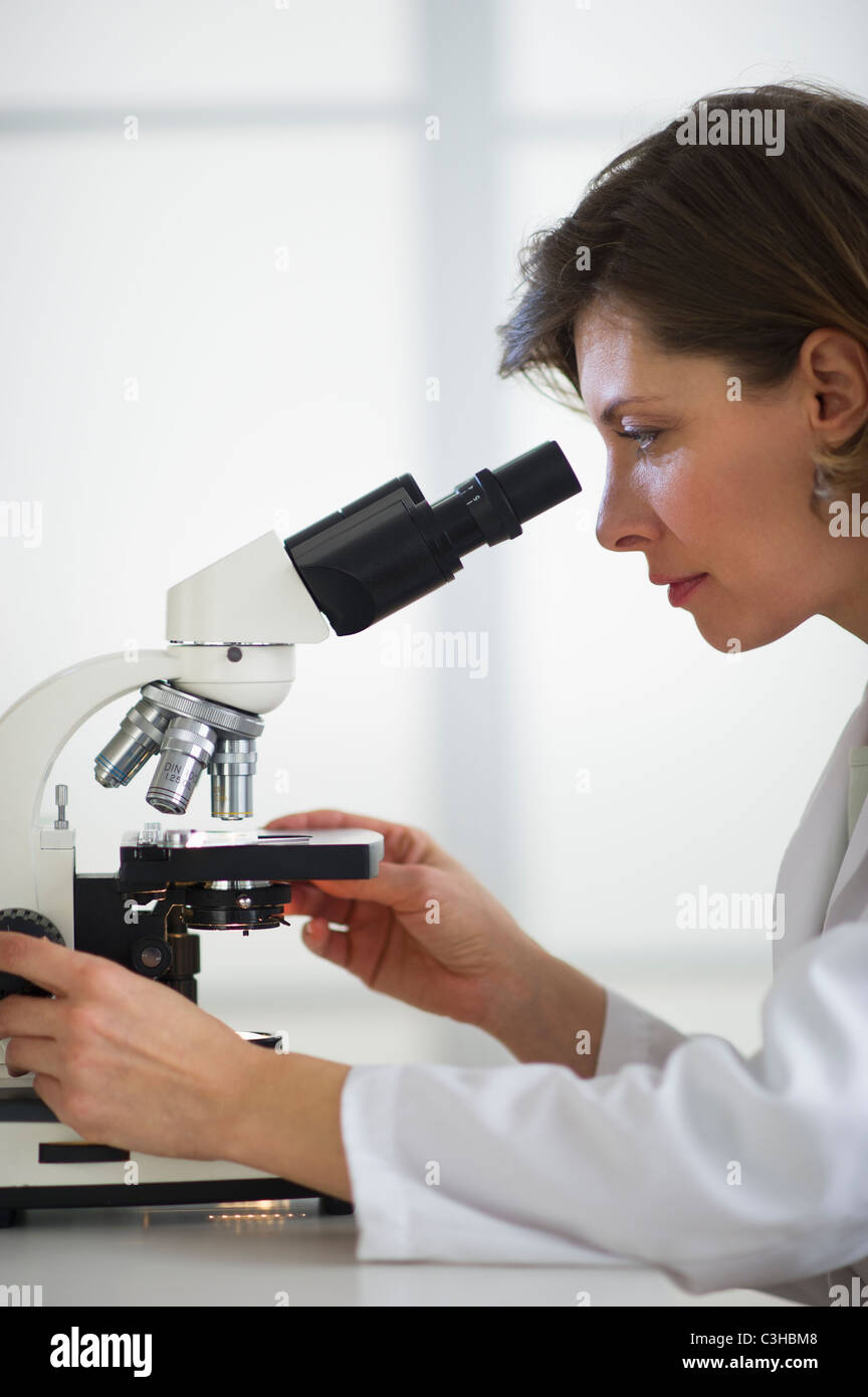 Woman in laboratory looking through microscope Stock Photo - Alamy