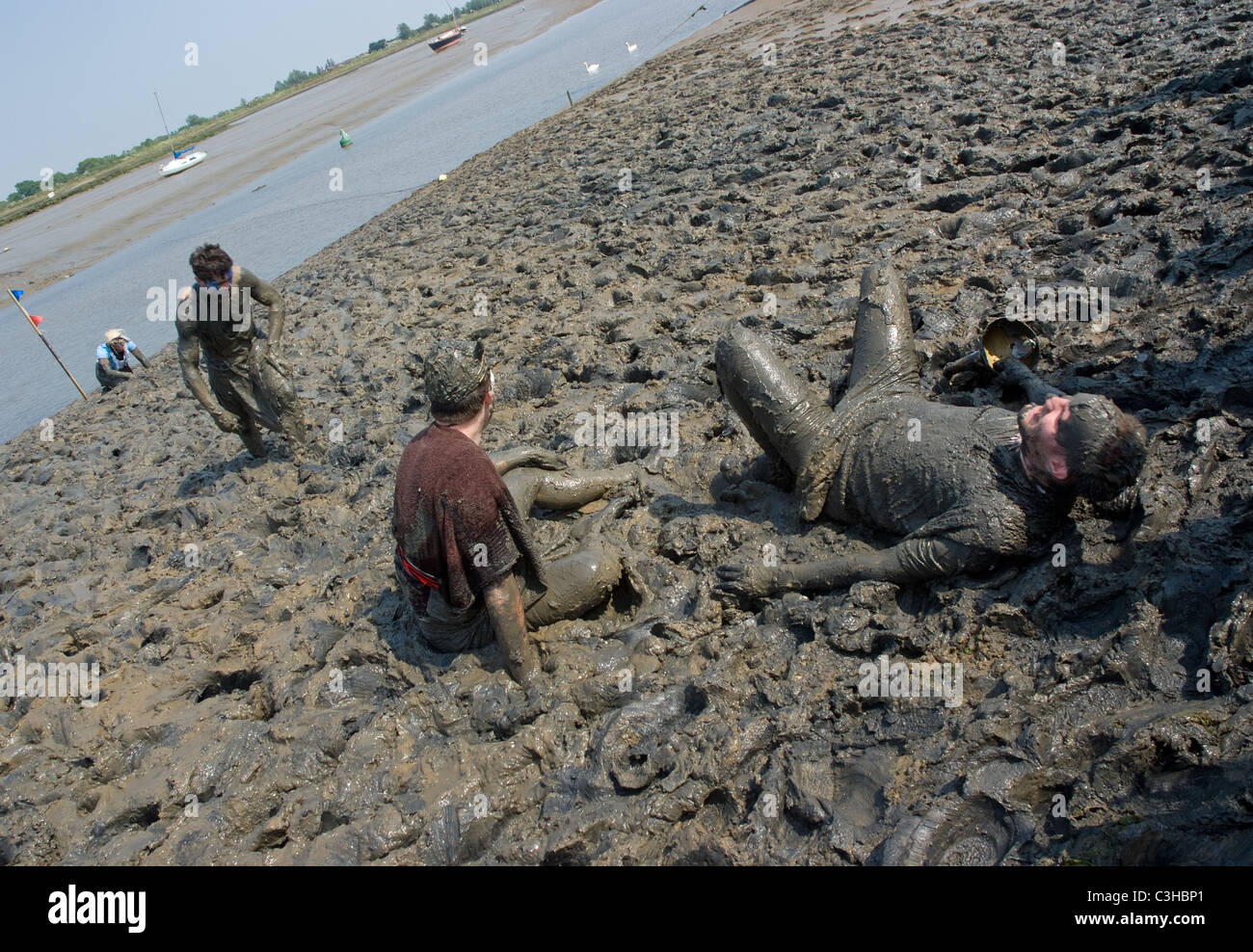 three competitors collapse in the mud towards the finish line of the ...