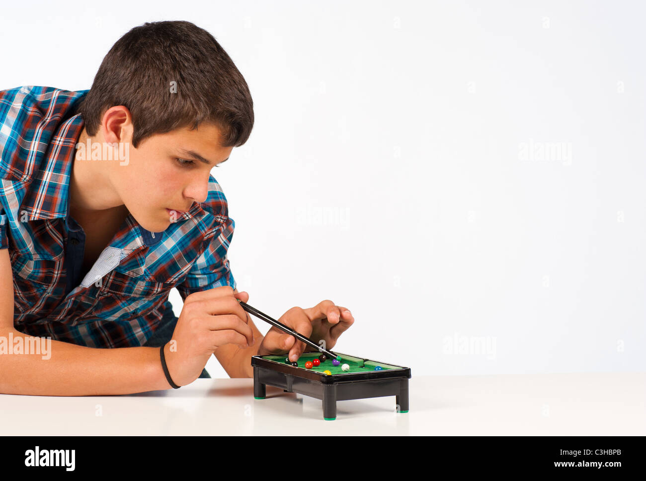 Teenager playing with a miniature snooker table Stock Photo - Alamy
