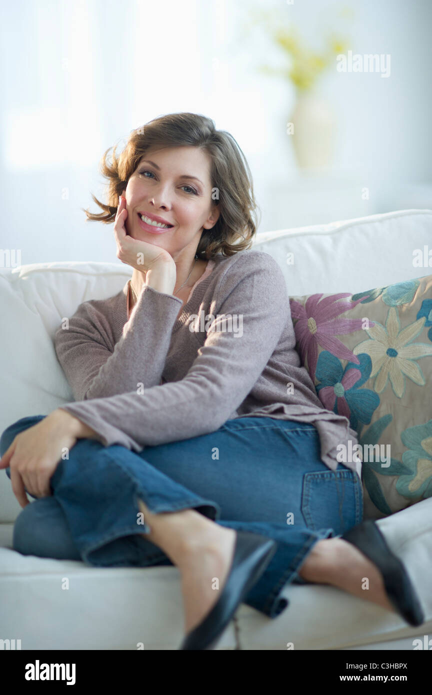 Portrait of smiling woman sitting on sofa Stock Photo - Alamy