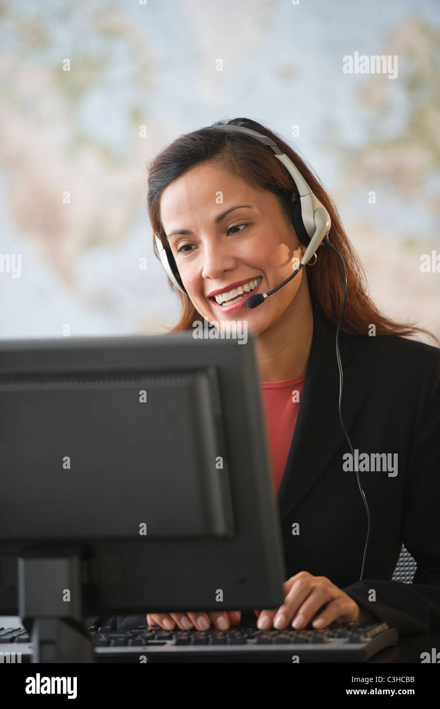 Female customer service representative with headset working on computer ...