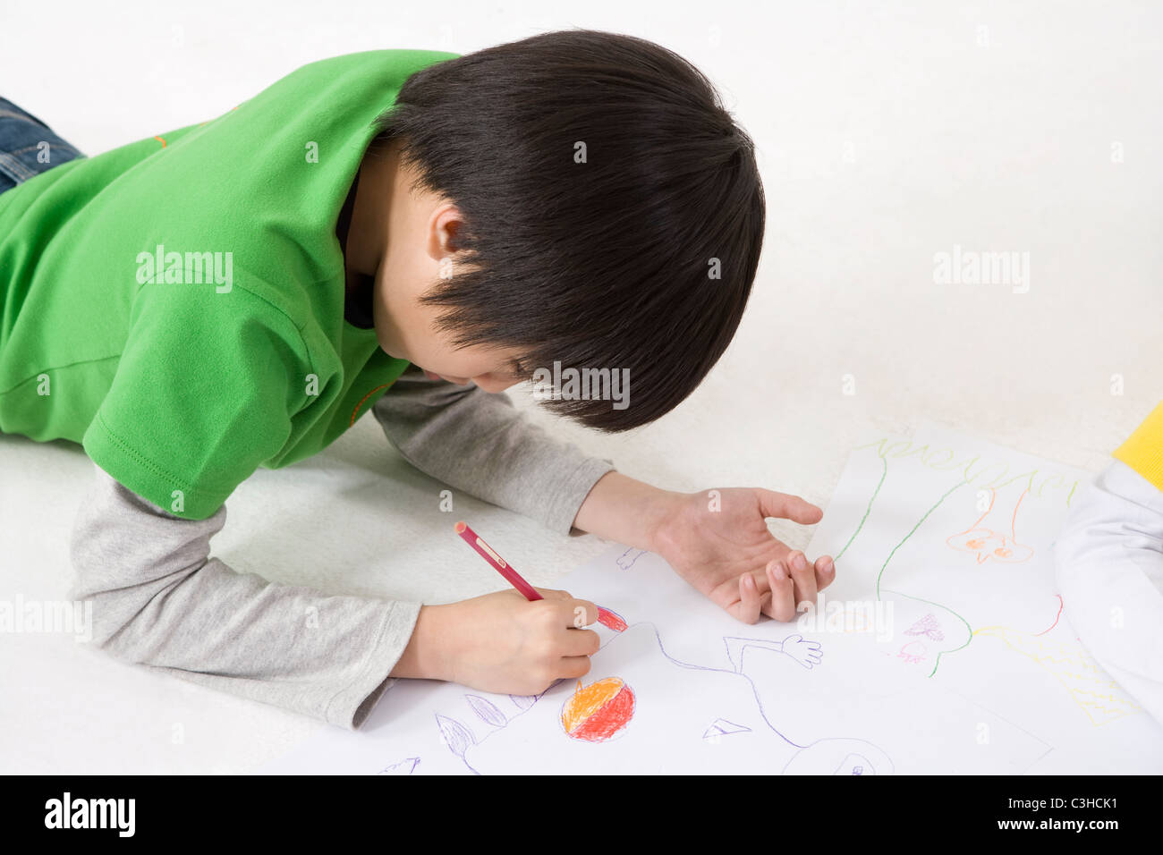 A young boy coloring while lying on the floor Stock Photo - Alamy