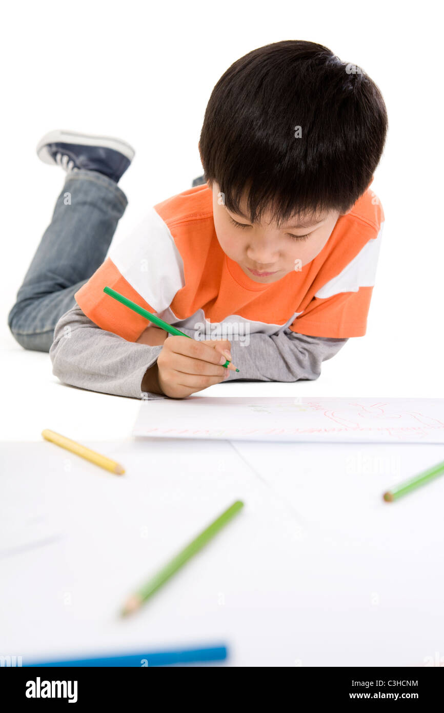 A young boy coloring while lying on the floor Stock Photo - Alamy