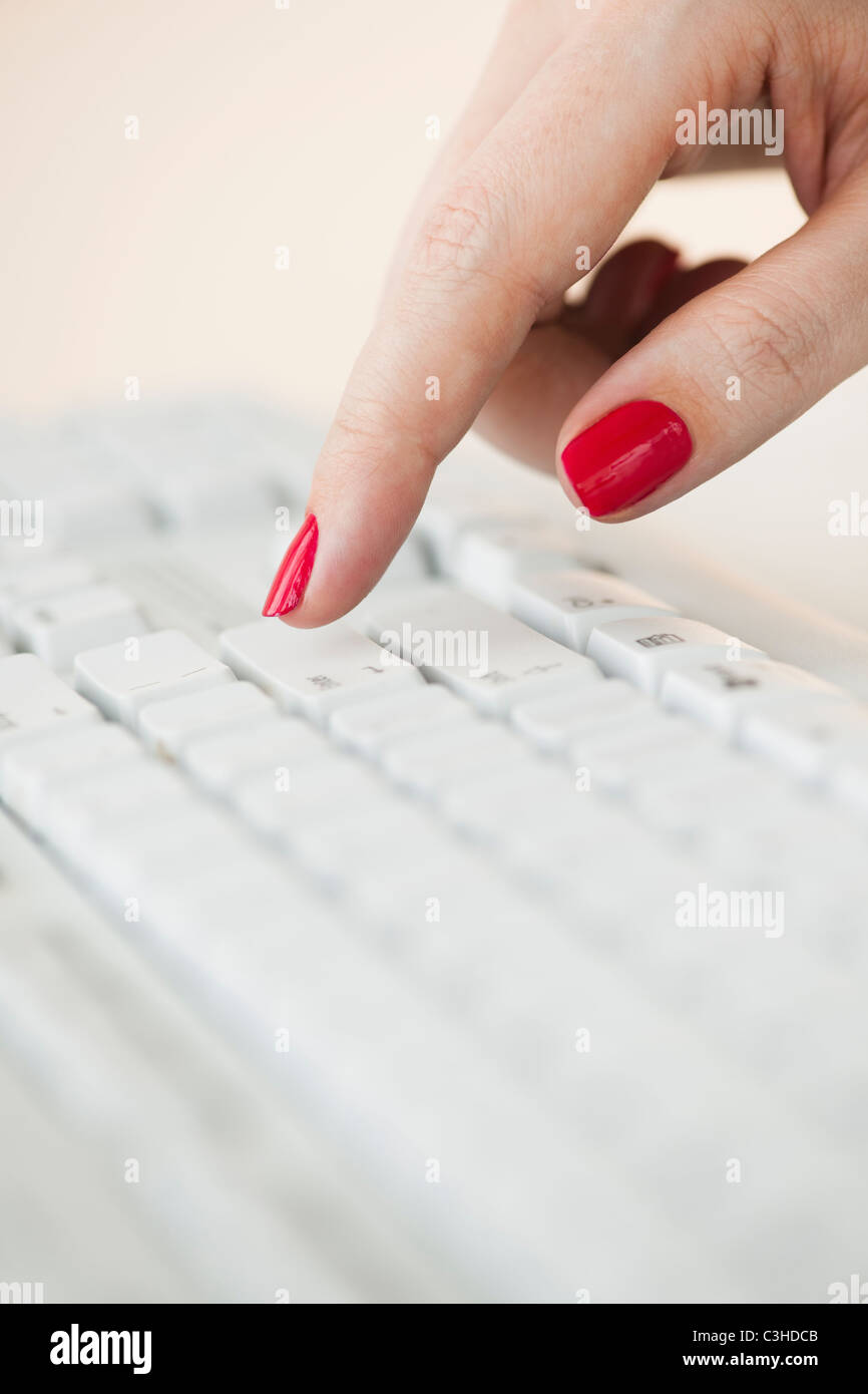 Close up of woman's finger with red nail polish typing on computer ...