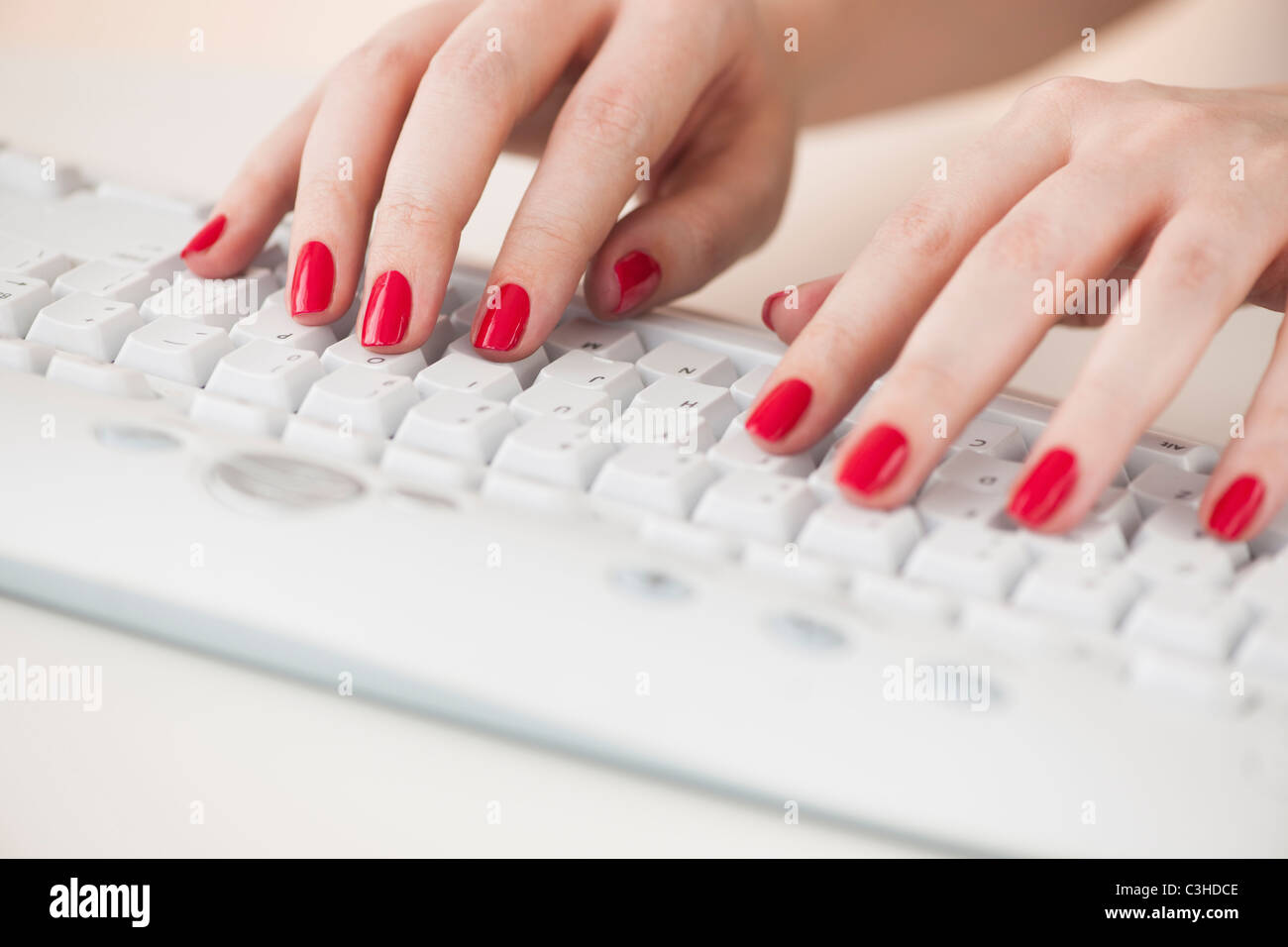 Close up of woman's fingers with red nail polish typing on computer ...