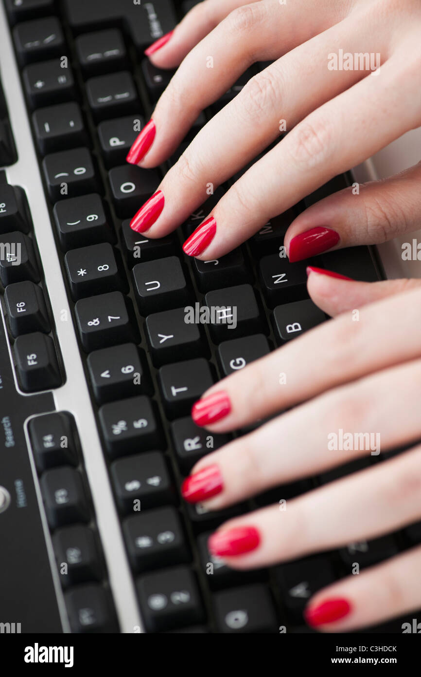 Close up of woman's fingers with red nail polish typing on computer ...