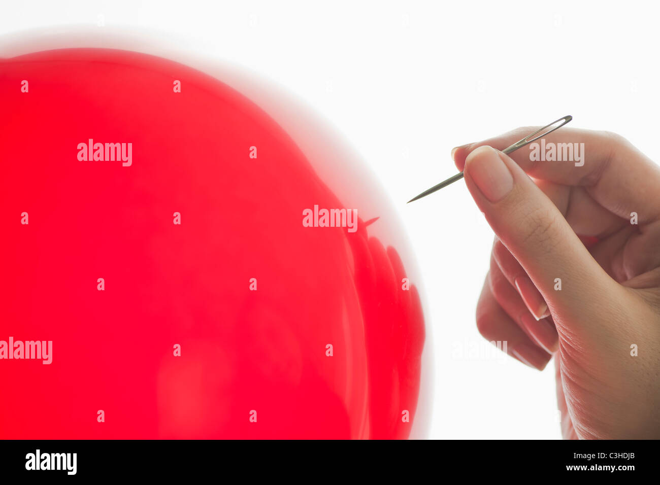 Studio shot of woman holding needle close to red balloon Stock Photo ...