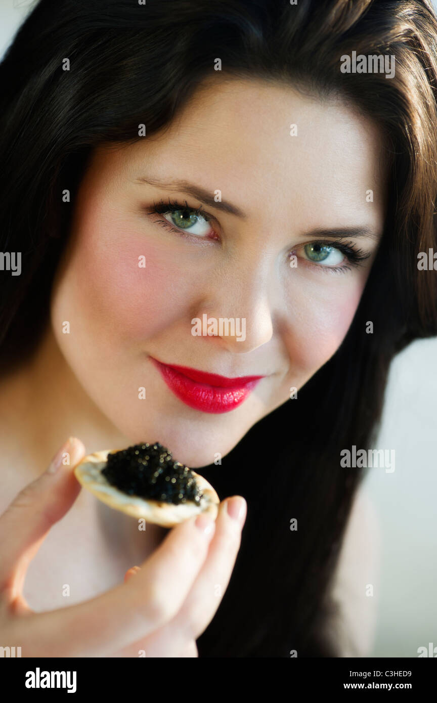Portrait of young woman eating caviar snack Stock Photo - Alamy