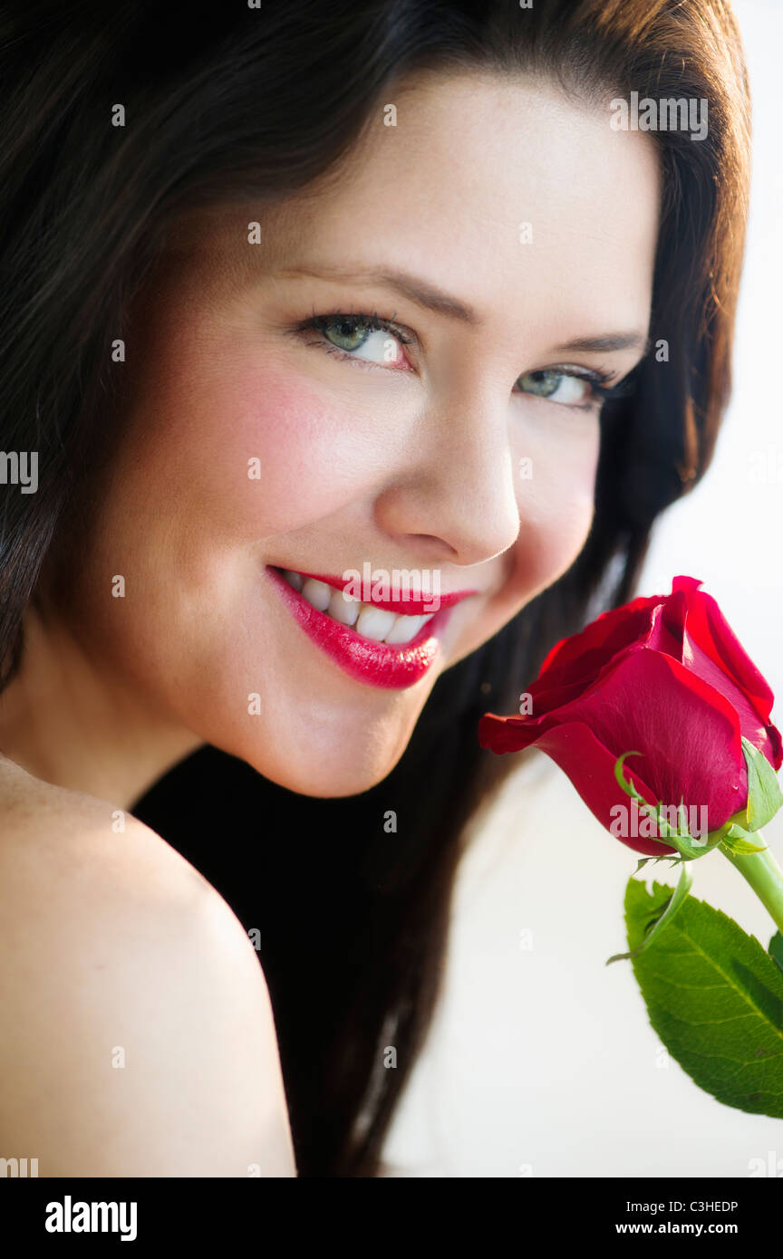 Studio shot of woman smelling red rose Stock Photo - Alamy