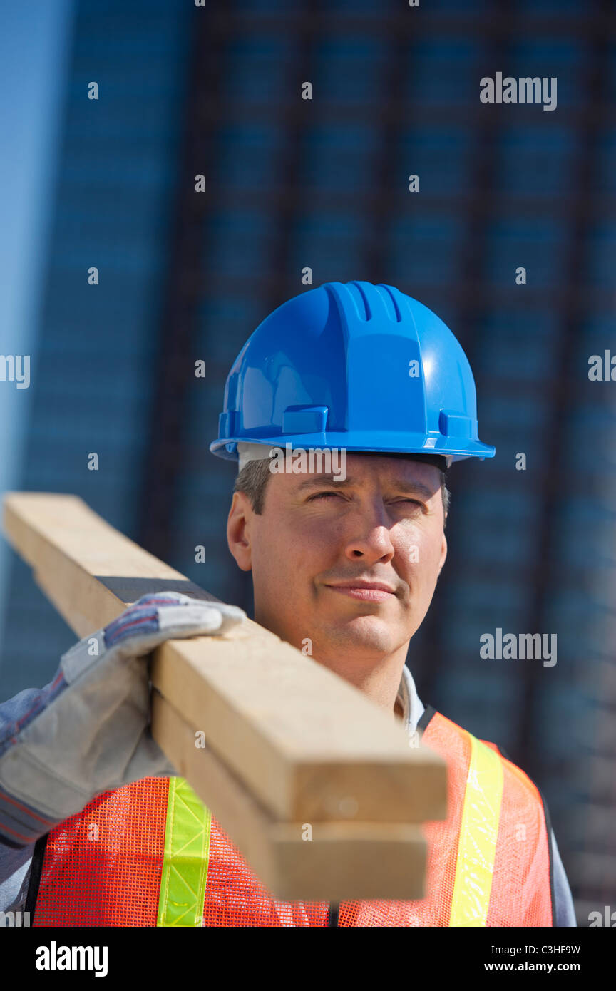 Construction worker carrying planks Stock Photo - Alamy
