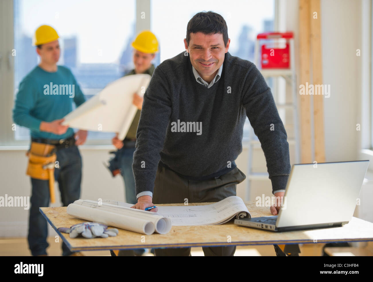 Architect preparing blueprint, construction workers in background Stock ...
