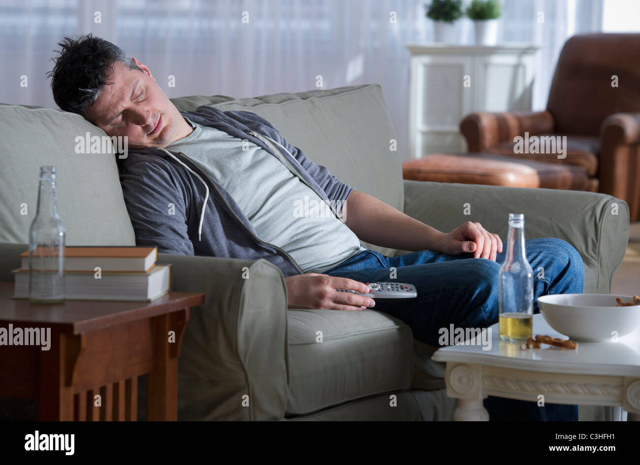 Man sitting on sofa, holding remote control and sleeping Stock Photo ...