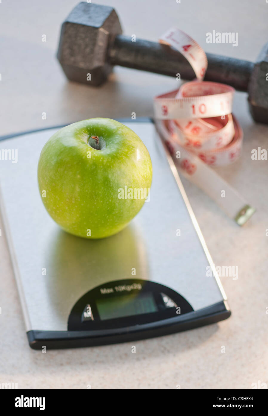 Green apple on weight scale, tape measure and exercise weight in ... Green apple on weight scale, tape measure and exercise weight in ...