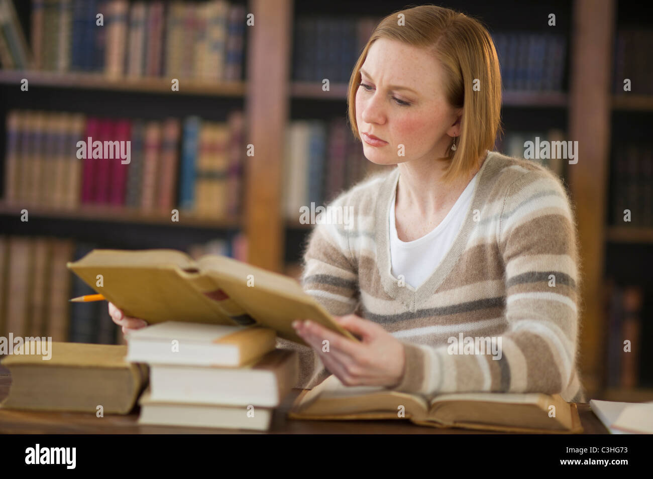 Woman reading book in library Stock Photo - Alamy