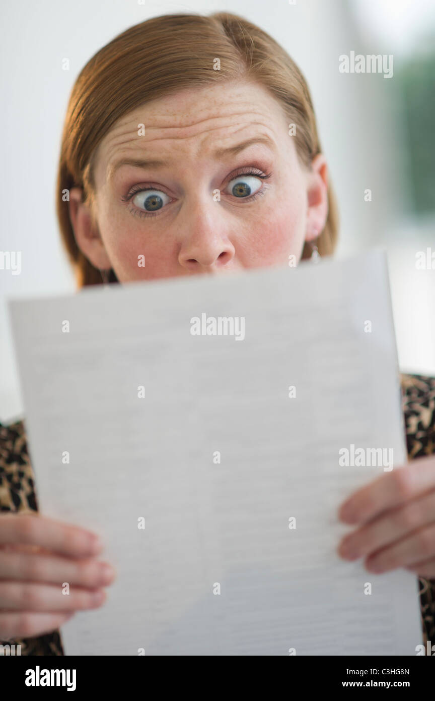 Woman reading document looking surprised Stock Photo - Alamy