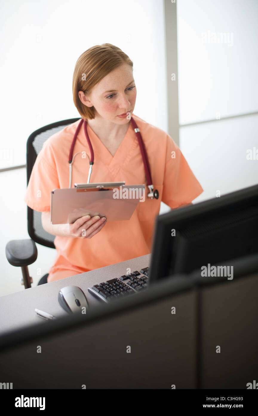 Female nurse reading medical records Stock Photo - Alamy