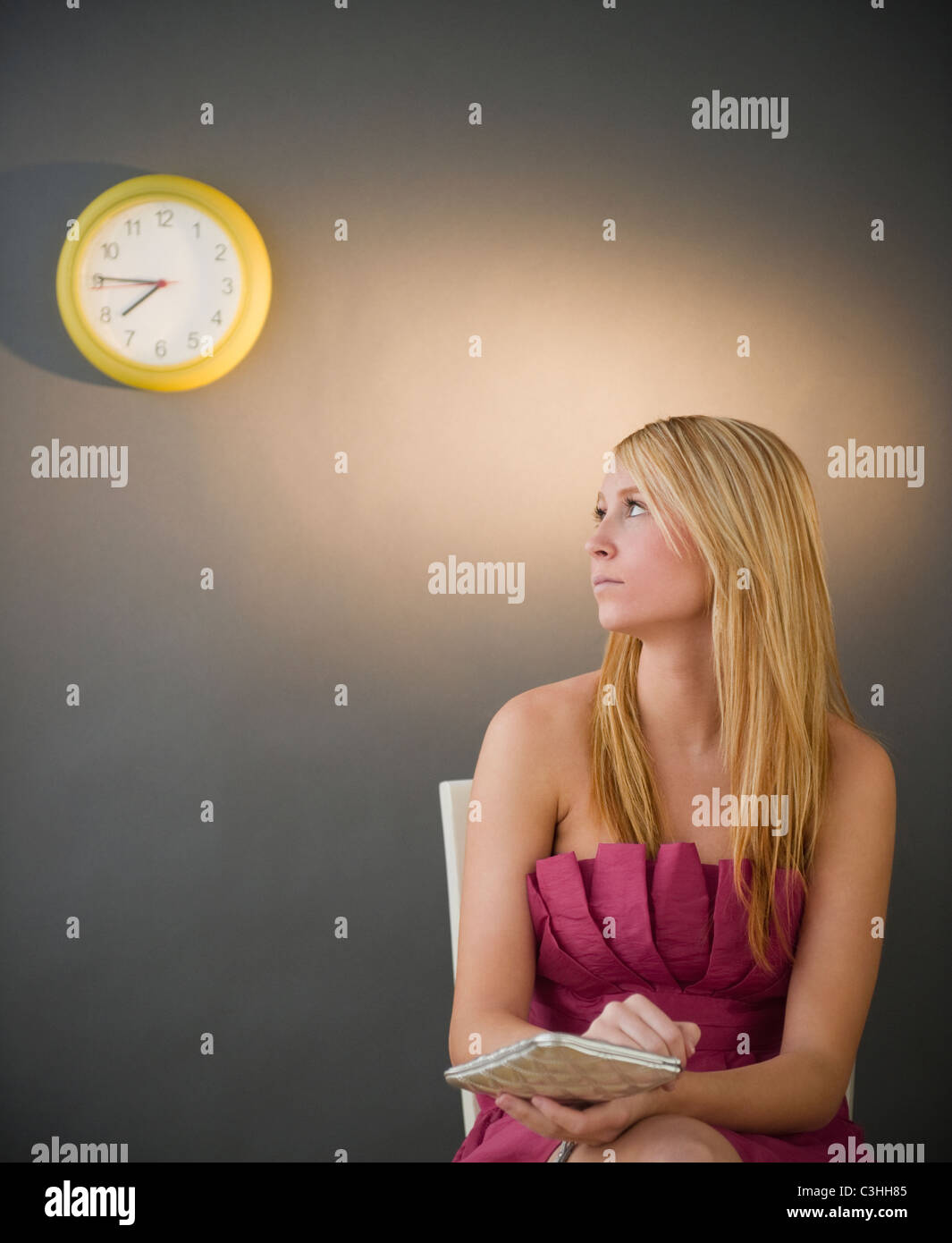 Young woman in evening wear looking at clock Stock Photo - Alamy