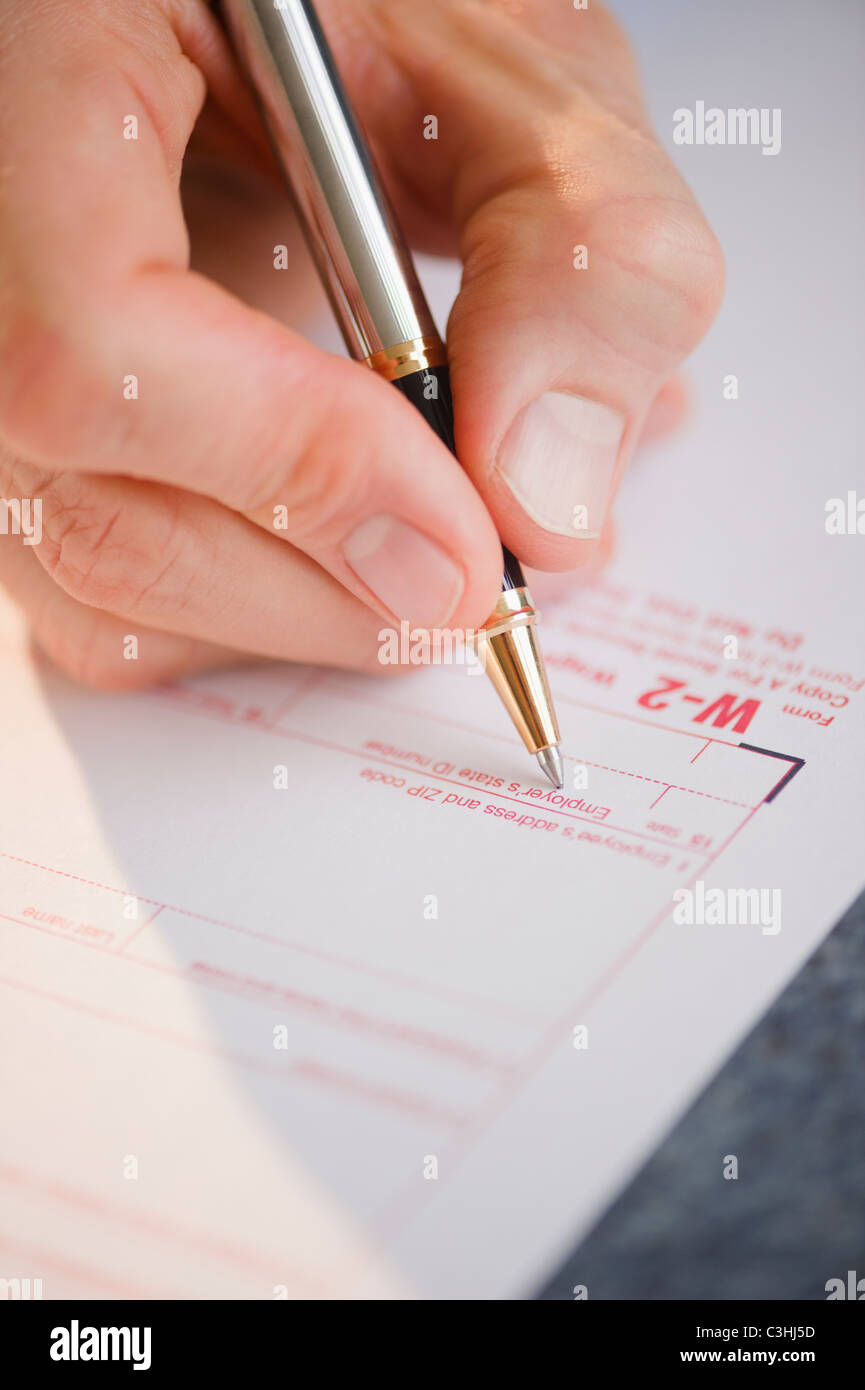 Hand filling tax form Stock Photo - Alamy