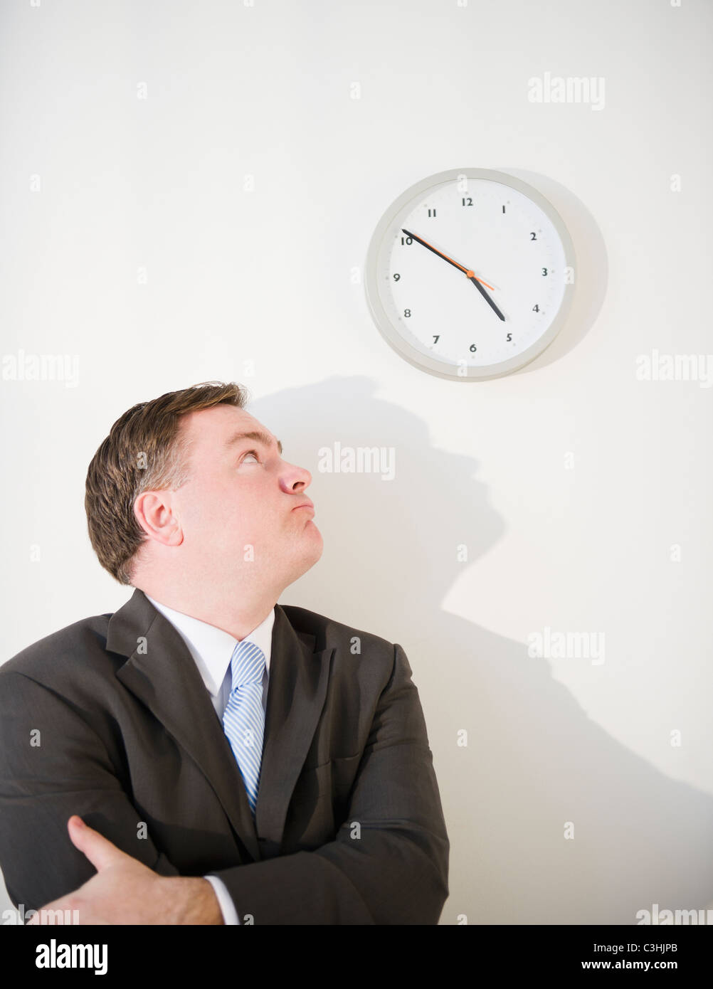 Businessman looking up at clock Stock Photo - Alamy